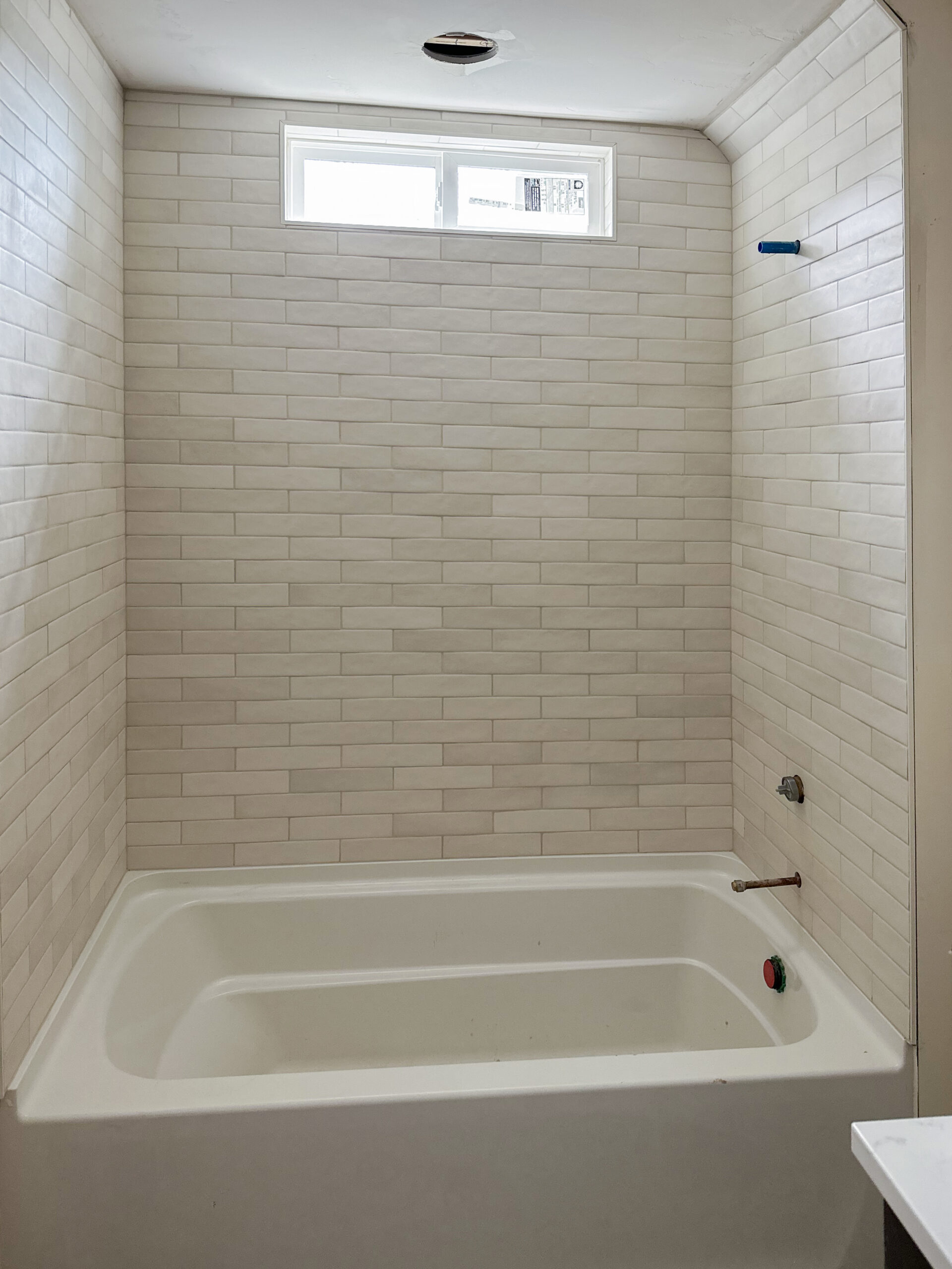Subway tile in the tub surround up to the ceiling with window at the ...